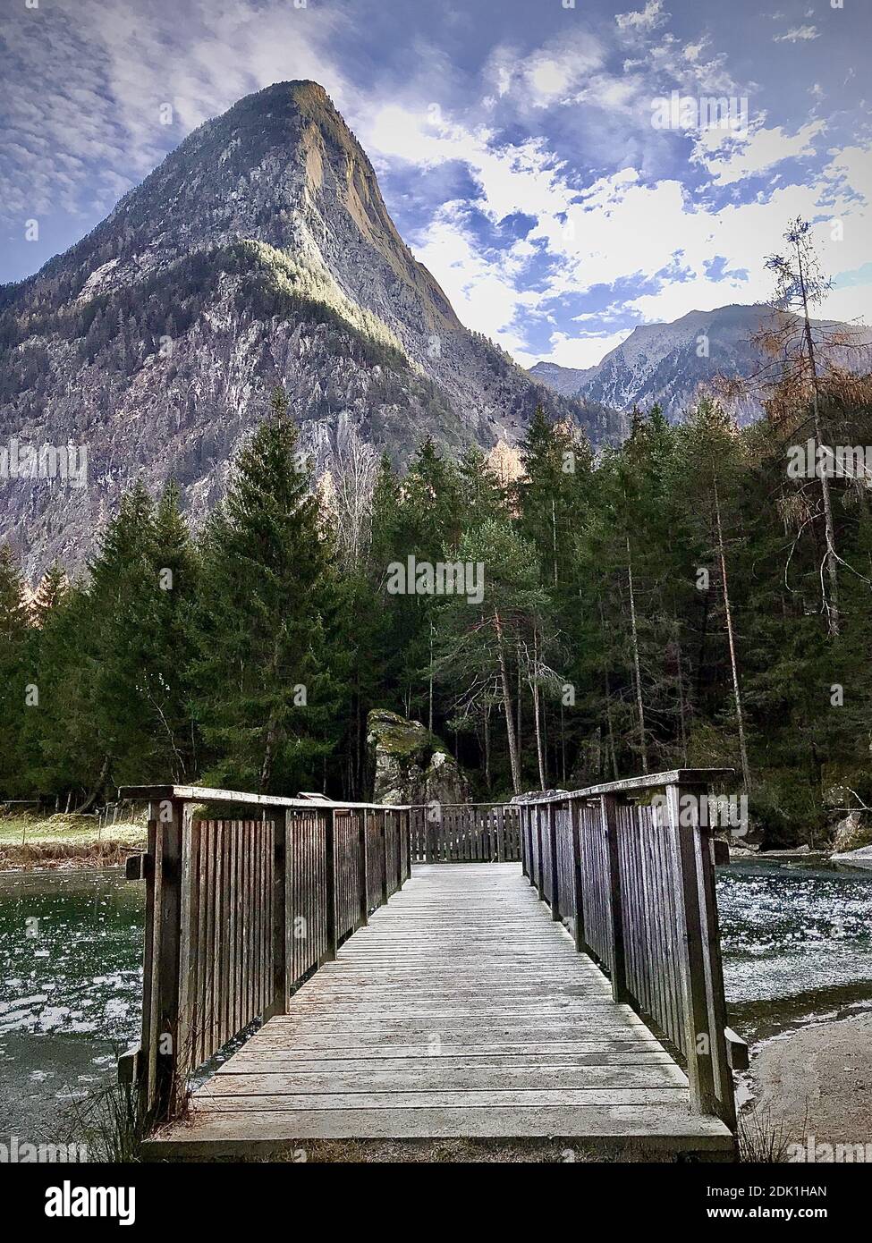 A vertical shot of a deck over the frozen lake leading to the forest ...