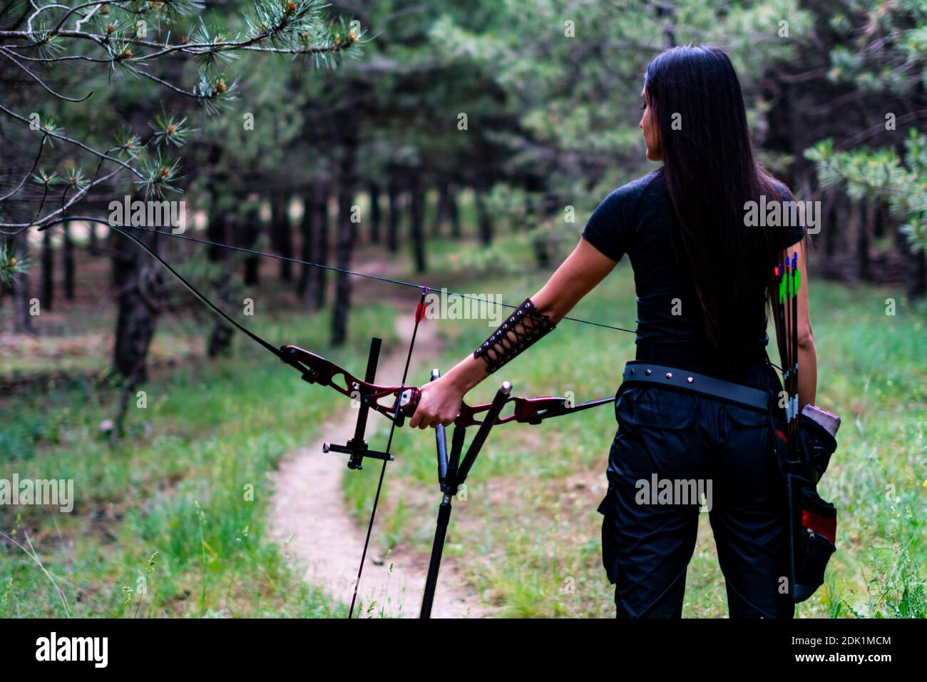A back view of a woman hunter holding a compound bow and arrow in a ...