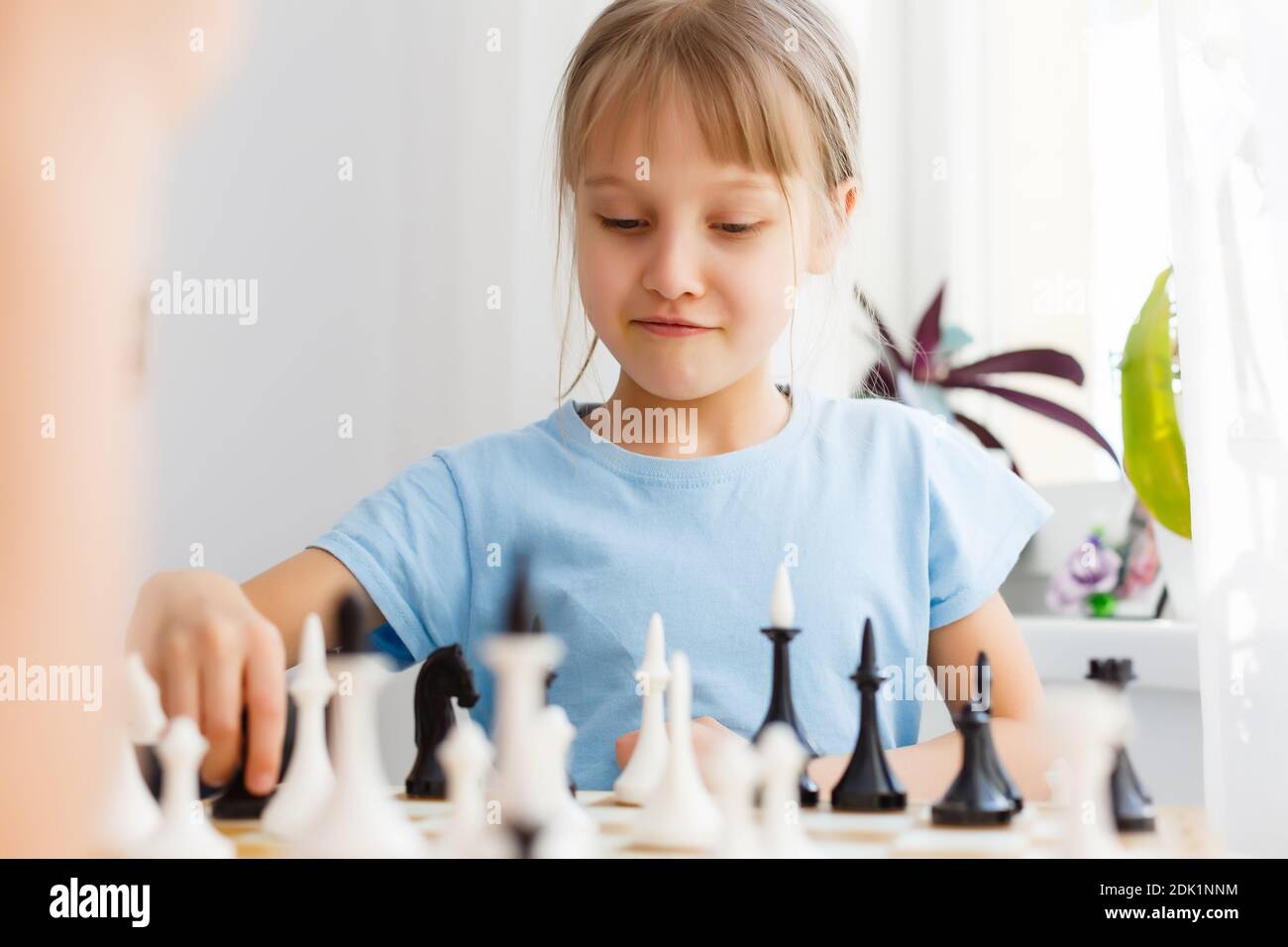 Little girl playing chess at a table Stock Photo - Alamy