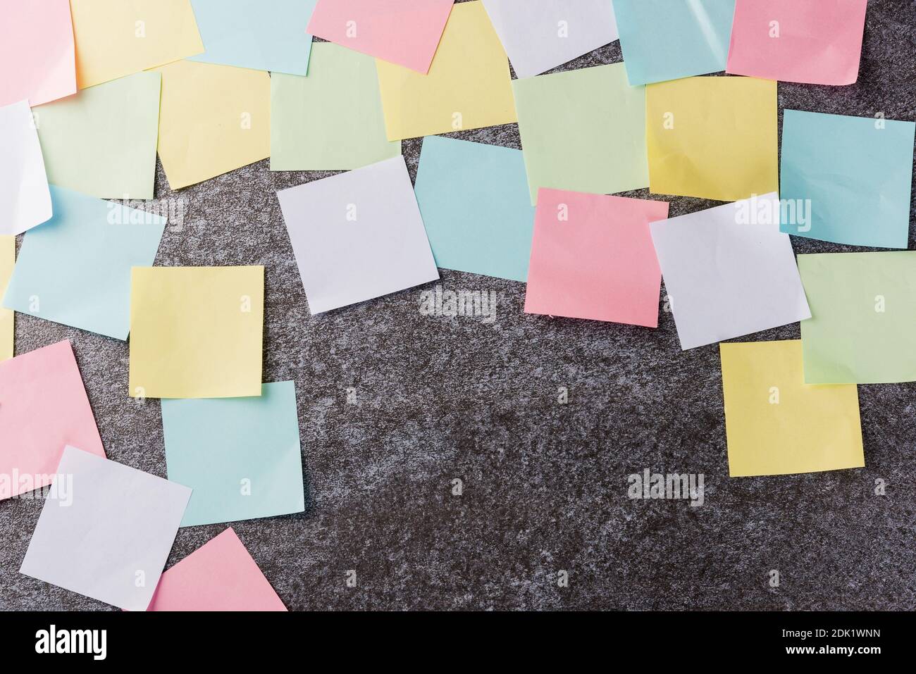 Many blank multicolored paper stick note list on concrete wall ...