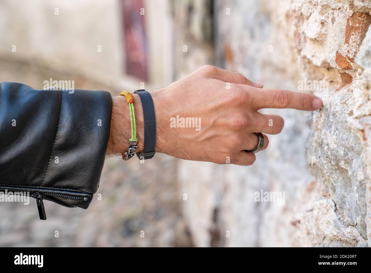 A closeup of a male hand wearing a leather jacket with bracelets and a ...