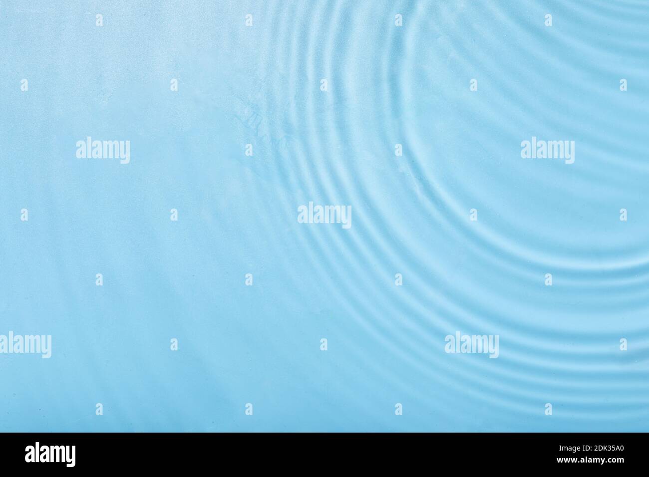 A top view closeup of waterdrops falling on the surface and forming a ...