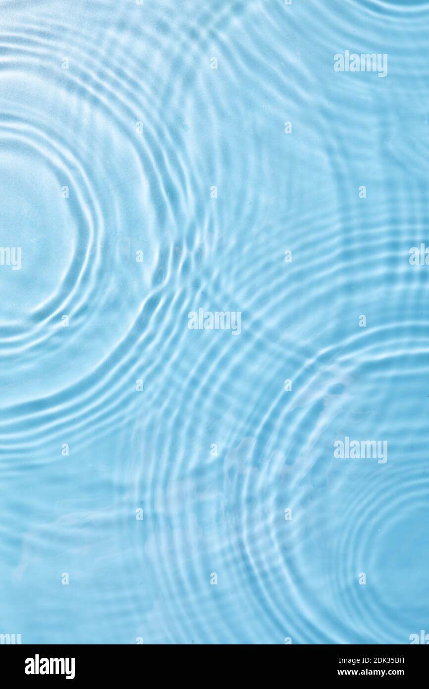 A top view closeup of waterdrops falling on the surface and forming a ...