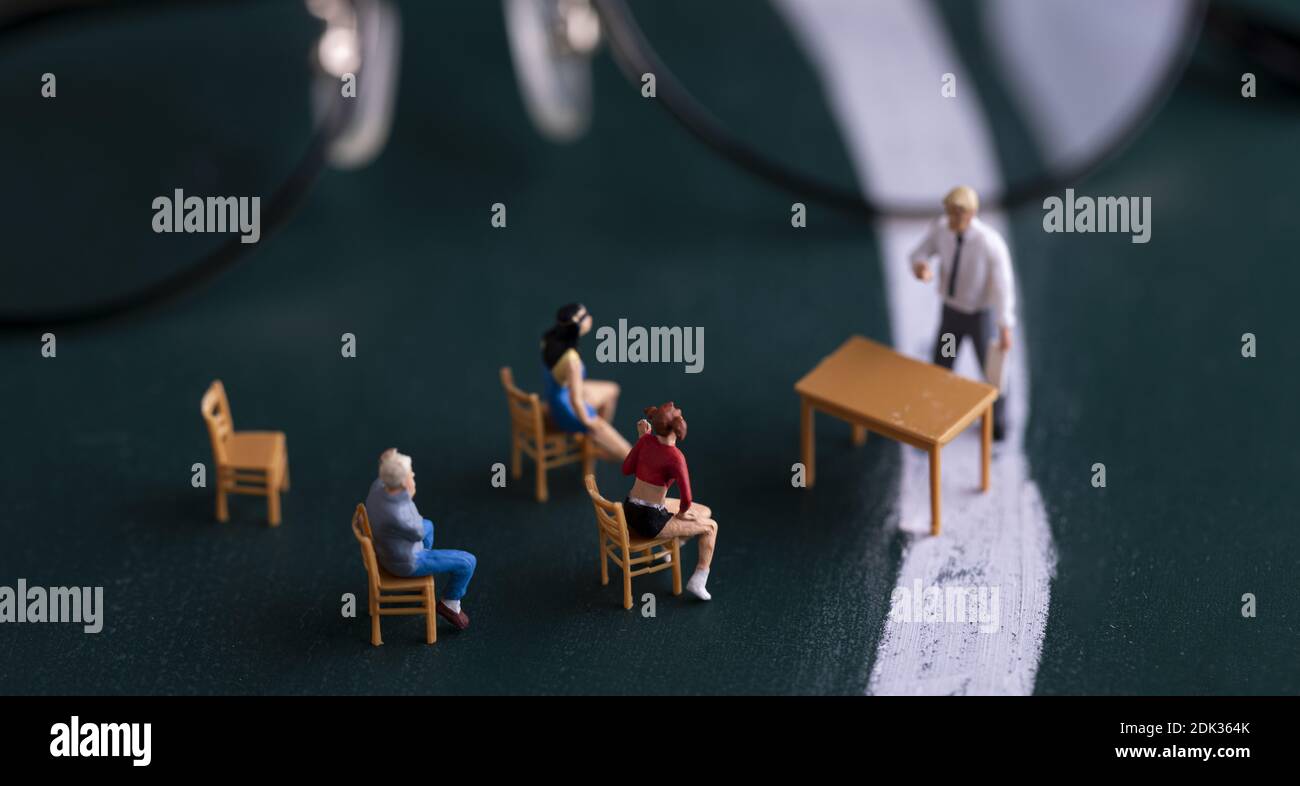 A closeup of tiny figures of a professor in front of the desk and ...