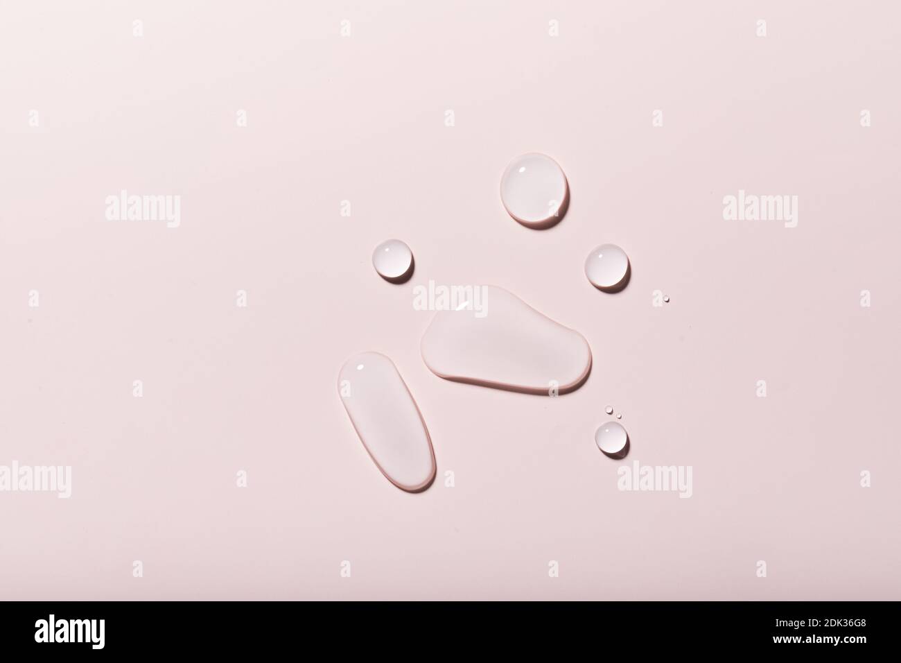 A top view closeup of multiple water drops on a light purple background ...