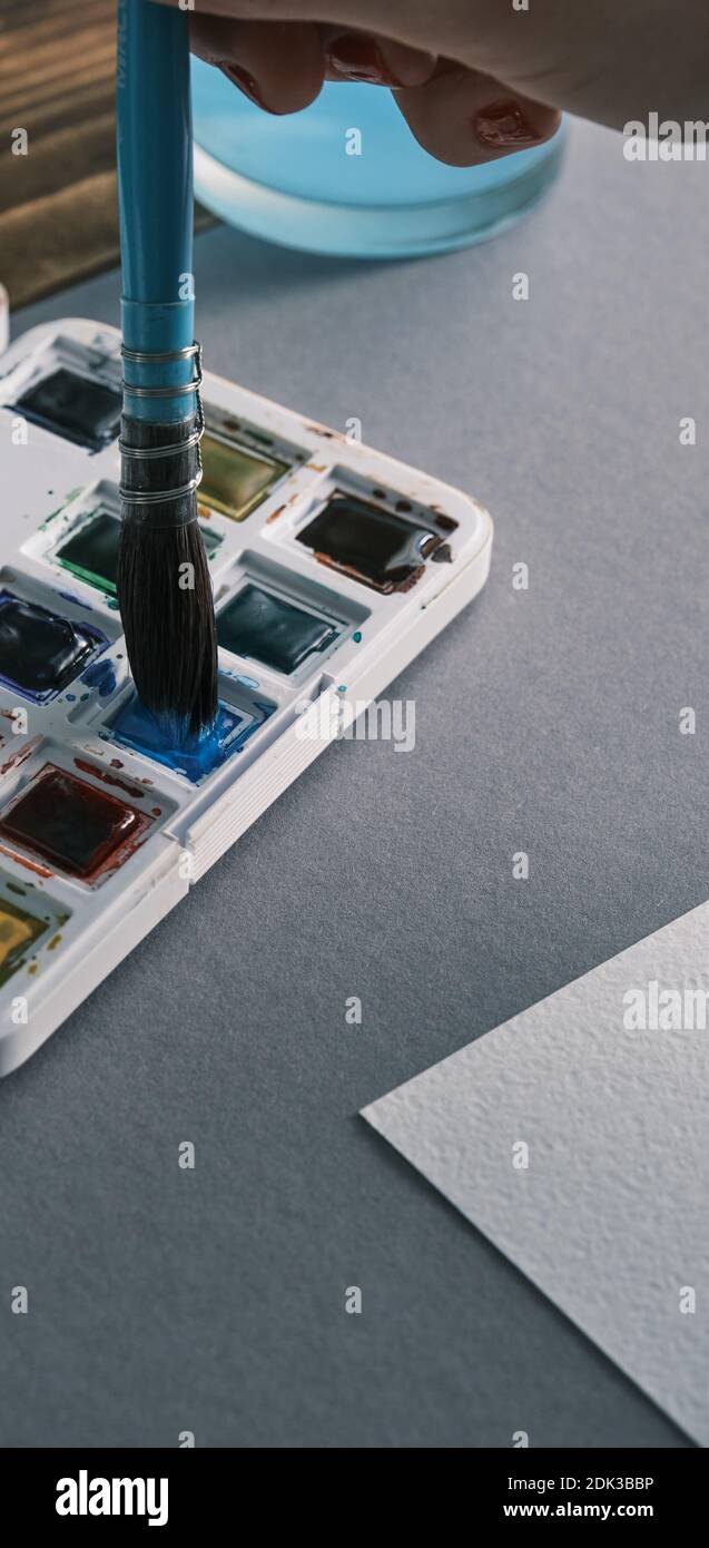 Female hand holding a brush on a clean white paper. Text rady. Painting ...