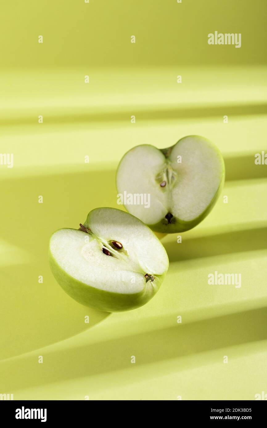 A vertical shot of fresh sliced green apples with shadow from window ...