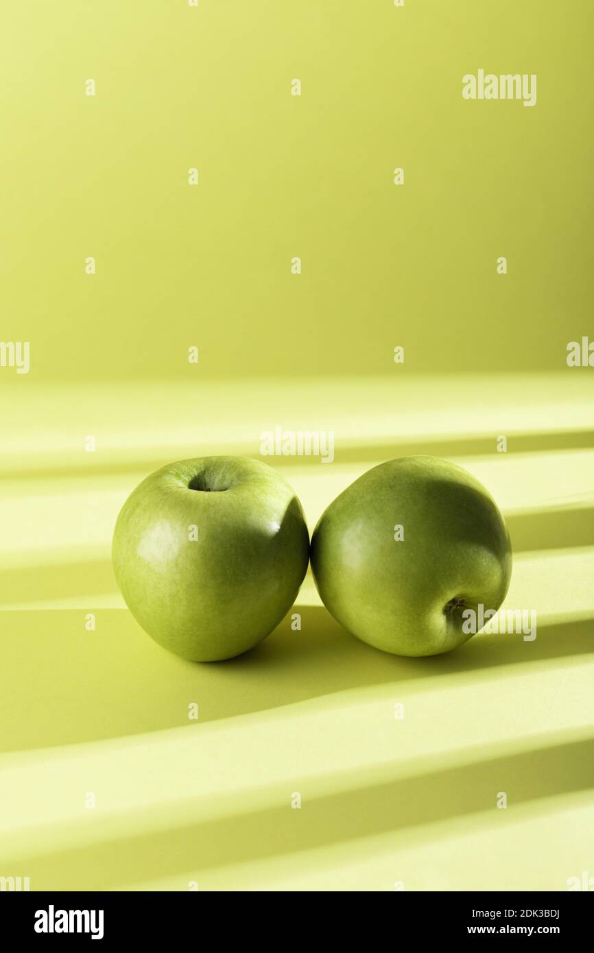 A vertical shot of fresh green apples with shadow from window isolated ...