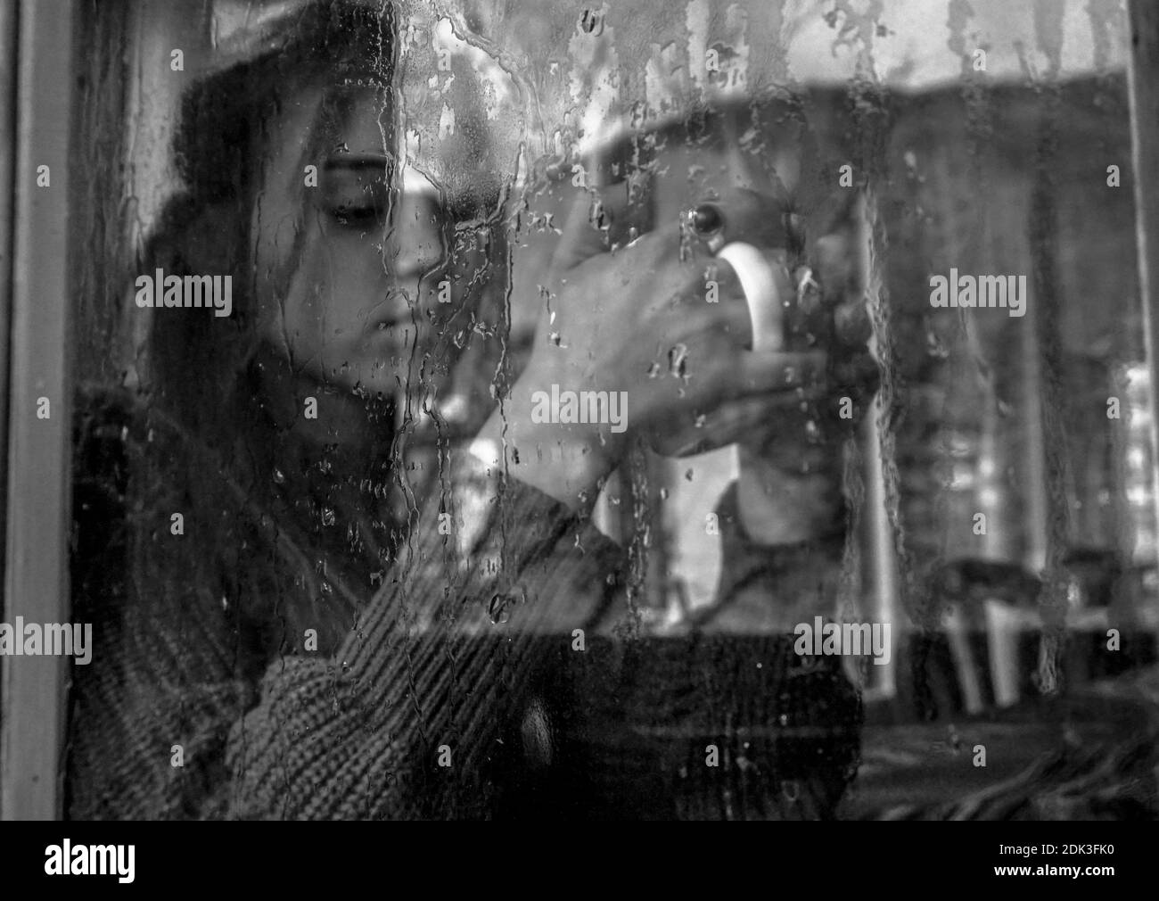 Woman looking through window rain Black and White Stock Photos & Images ...