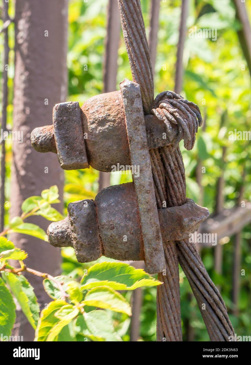 A vertical shot of a rustic bolt on a metal cable, outdoors during ...