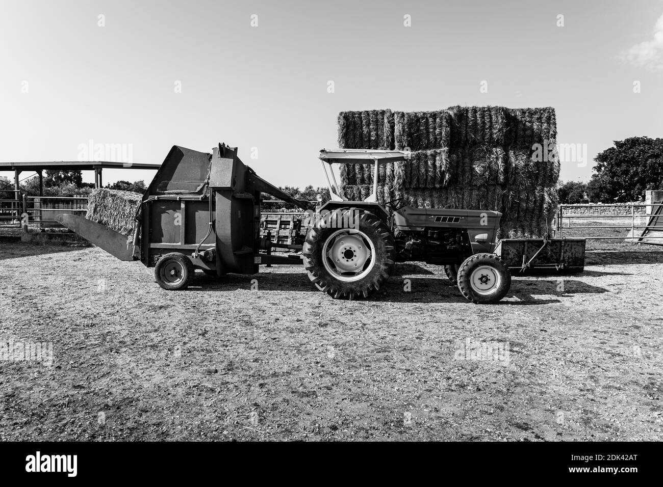 A grayscale shot of a tractor and hay blocks at a farm Stock Photo - Alamy