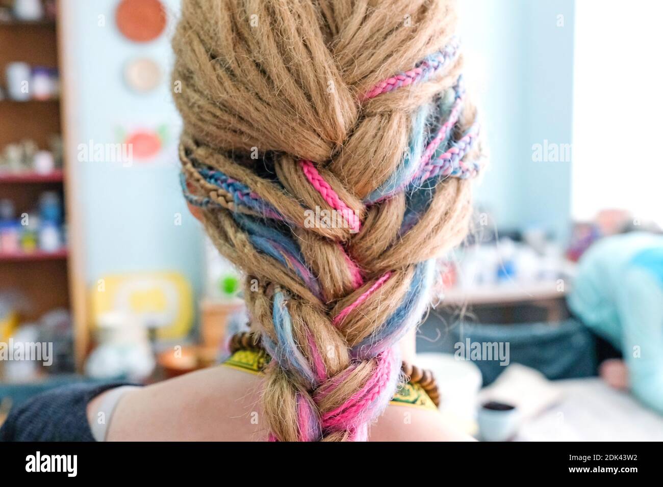 Colored braid on the girl's light head. Back view. The ribbons are ...