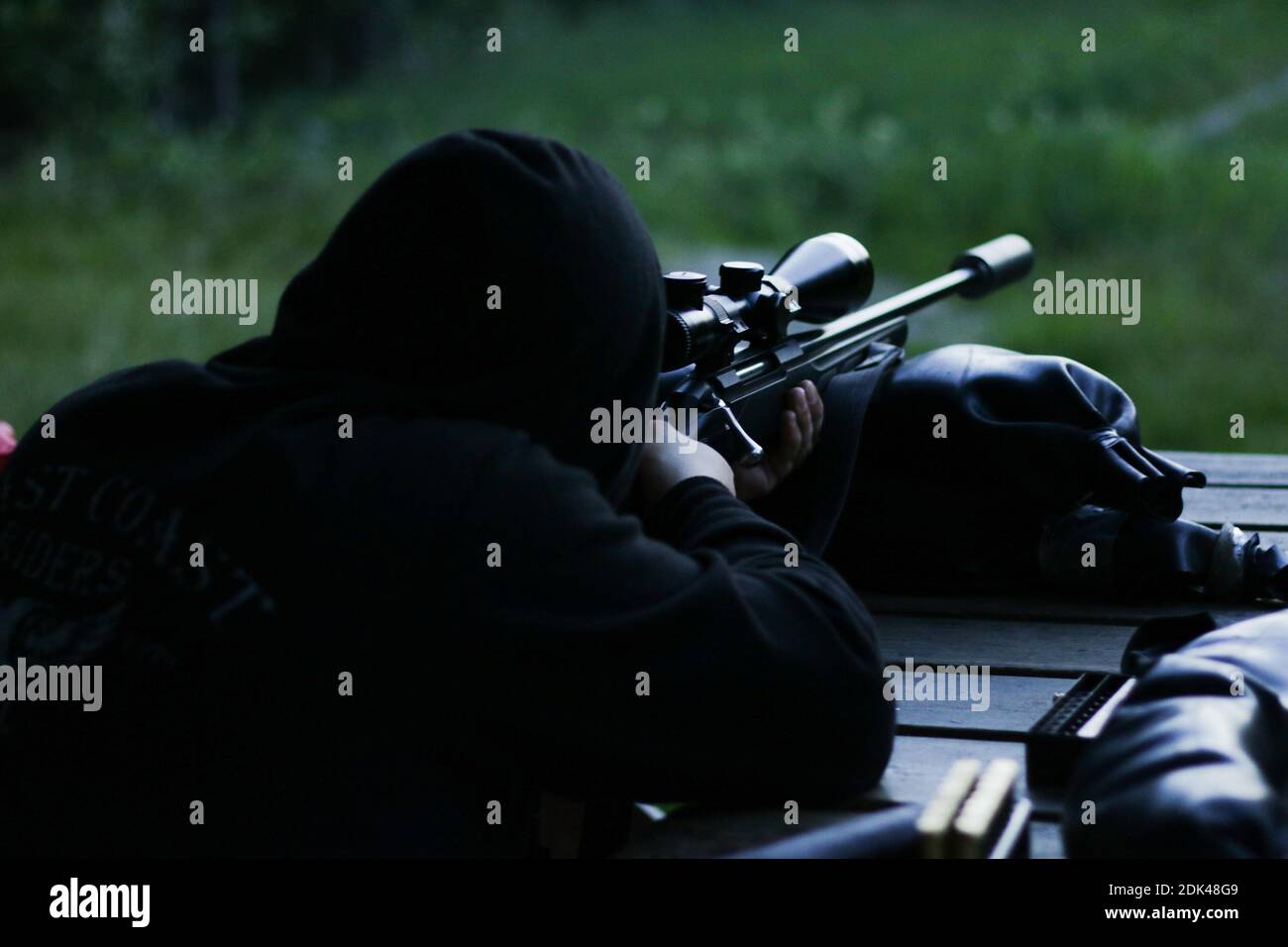 Rear View Of Man Aiming Sniper While Lying On Wooden Floor Stock Photo ...