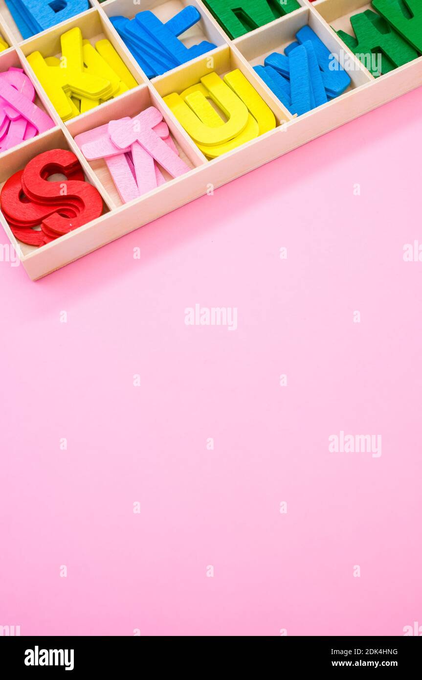 A vertical shot of colorful wooden letters in their case, placed on a ...