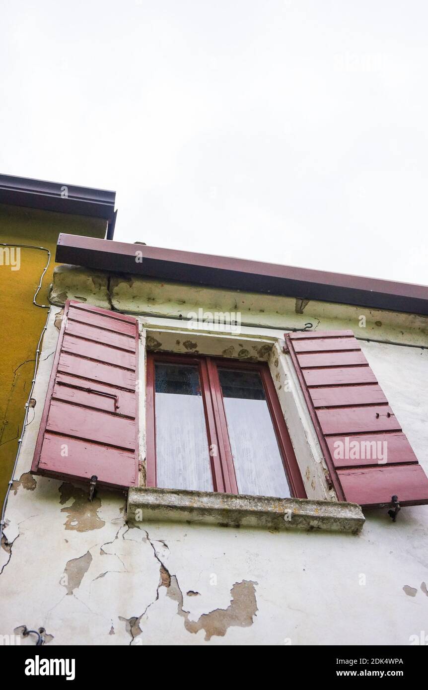 A vertical low angle shot of a building window with open brown wooden ...