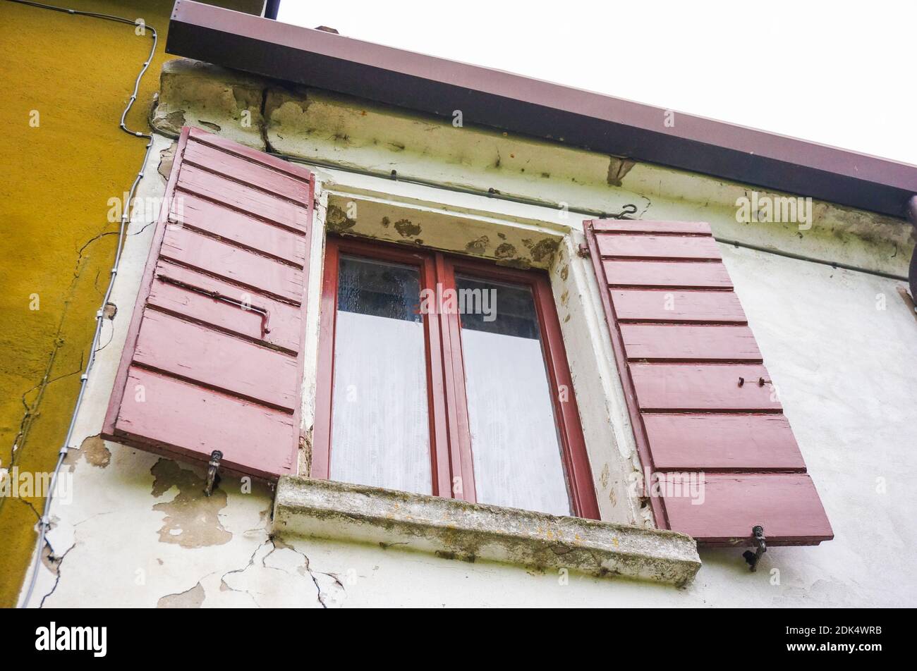 A low angle shot of a building window with open brown wooden shutters ...