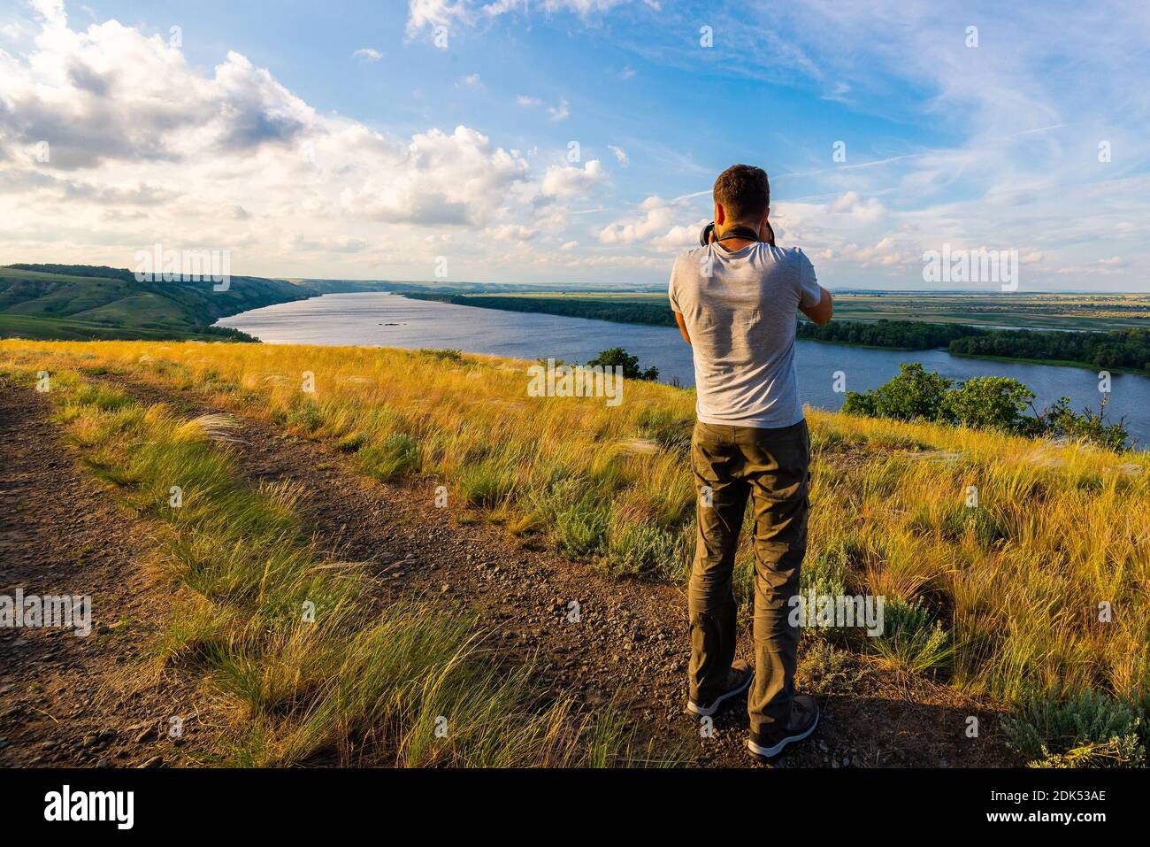 Back view of a photographer taking pictures of river landscape Stock ...