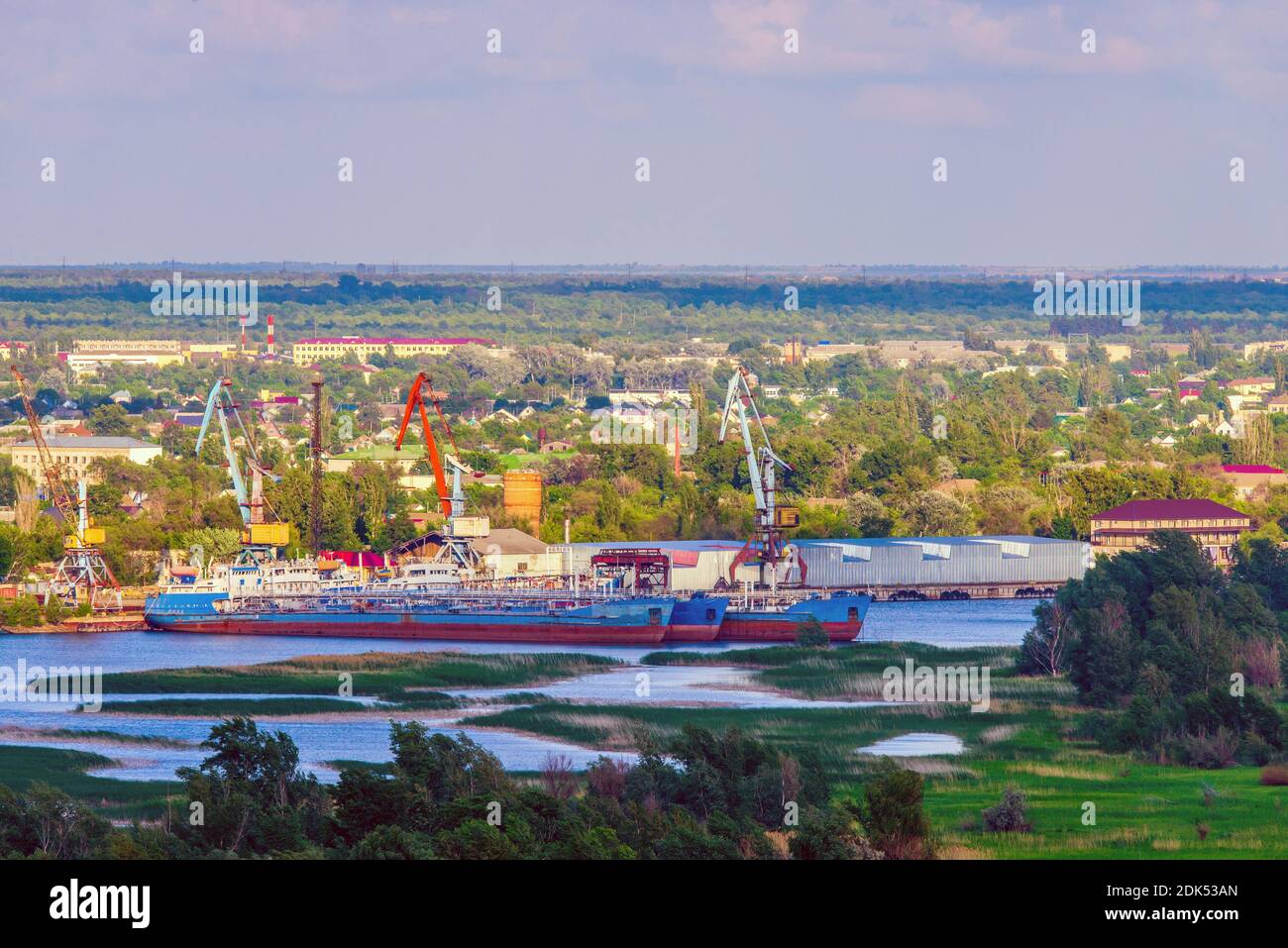 Portal cranes in the small port on a river load barges and cargo ships ...