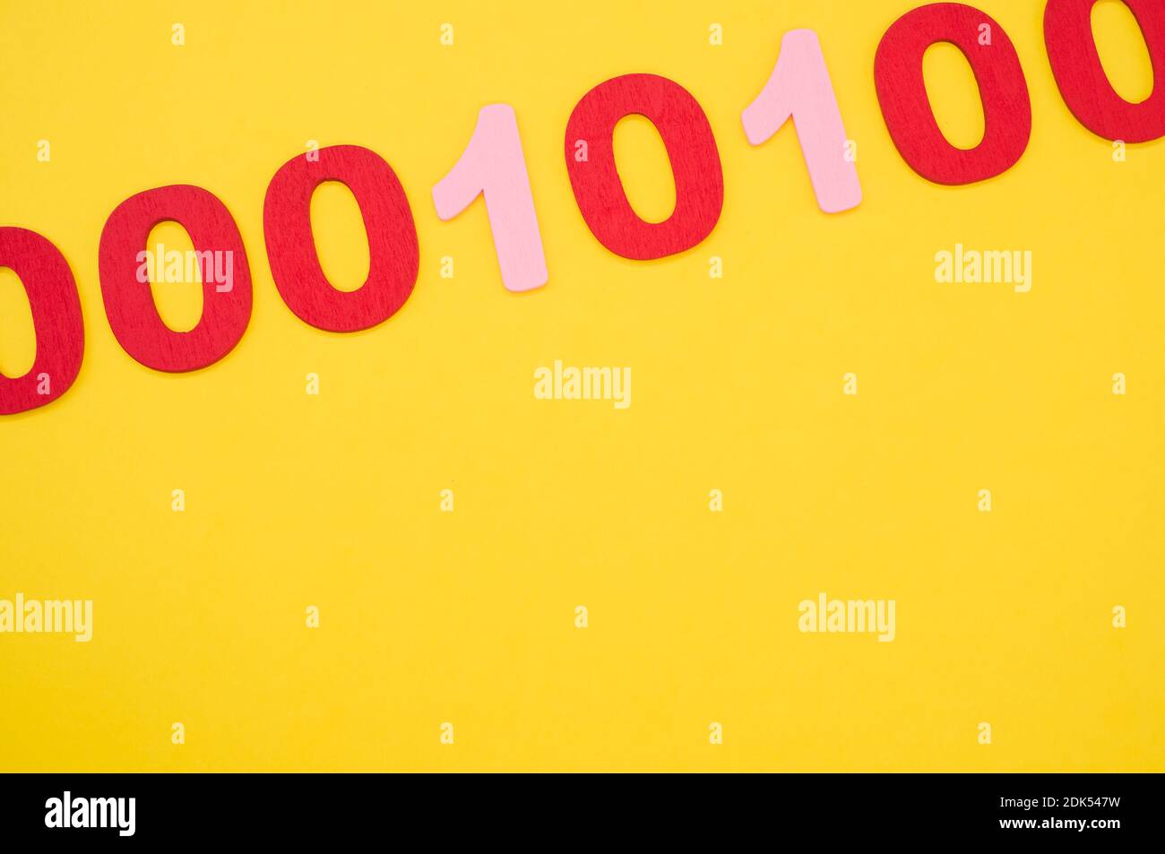 A top view of red and pink binary codes on a bright yellow surface ...