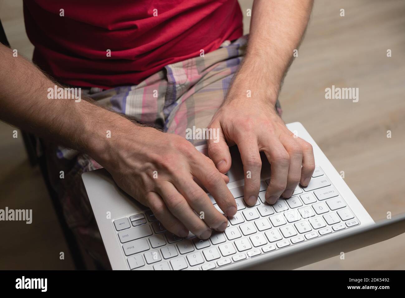 man is holding laptop on his lap and typing something on keyboard. Home ...