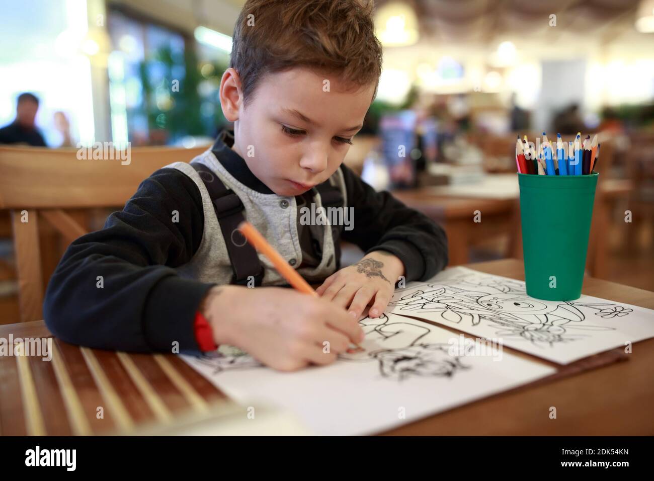 Child drawing at table in a cafe Stock Photo - Alamy