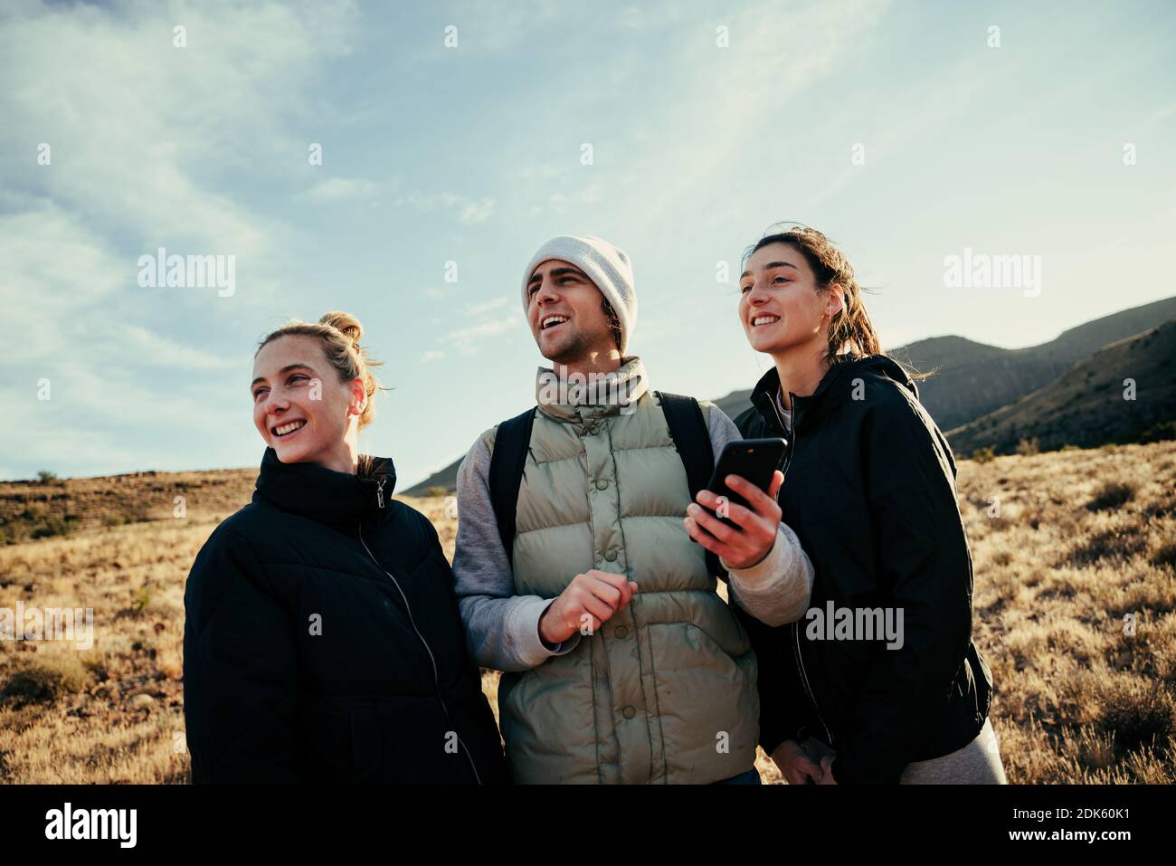 group of friends on adventure smiling while hiking through mountain ...