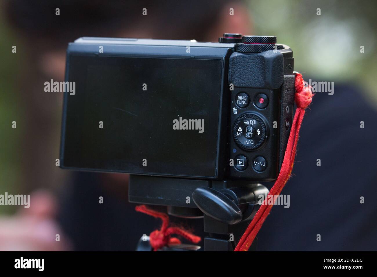 A closeup shot of a digital camera shooting with a blurry person in the ...