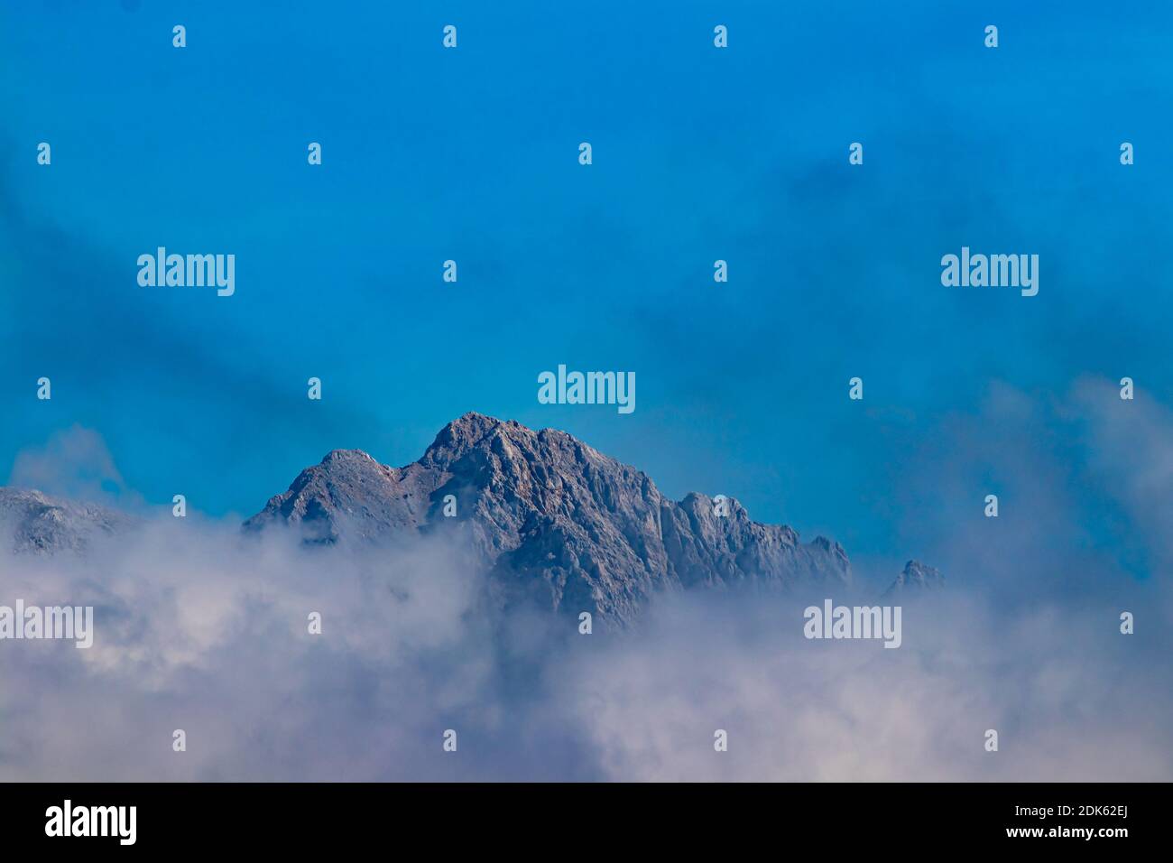 Mountain peak looking out from mist Stock Photo - Alamy