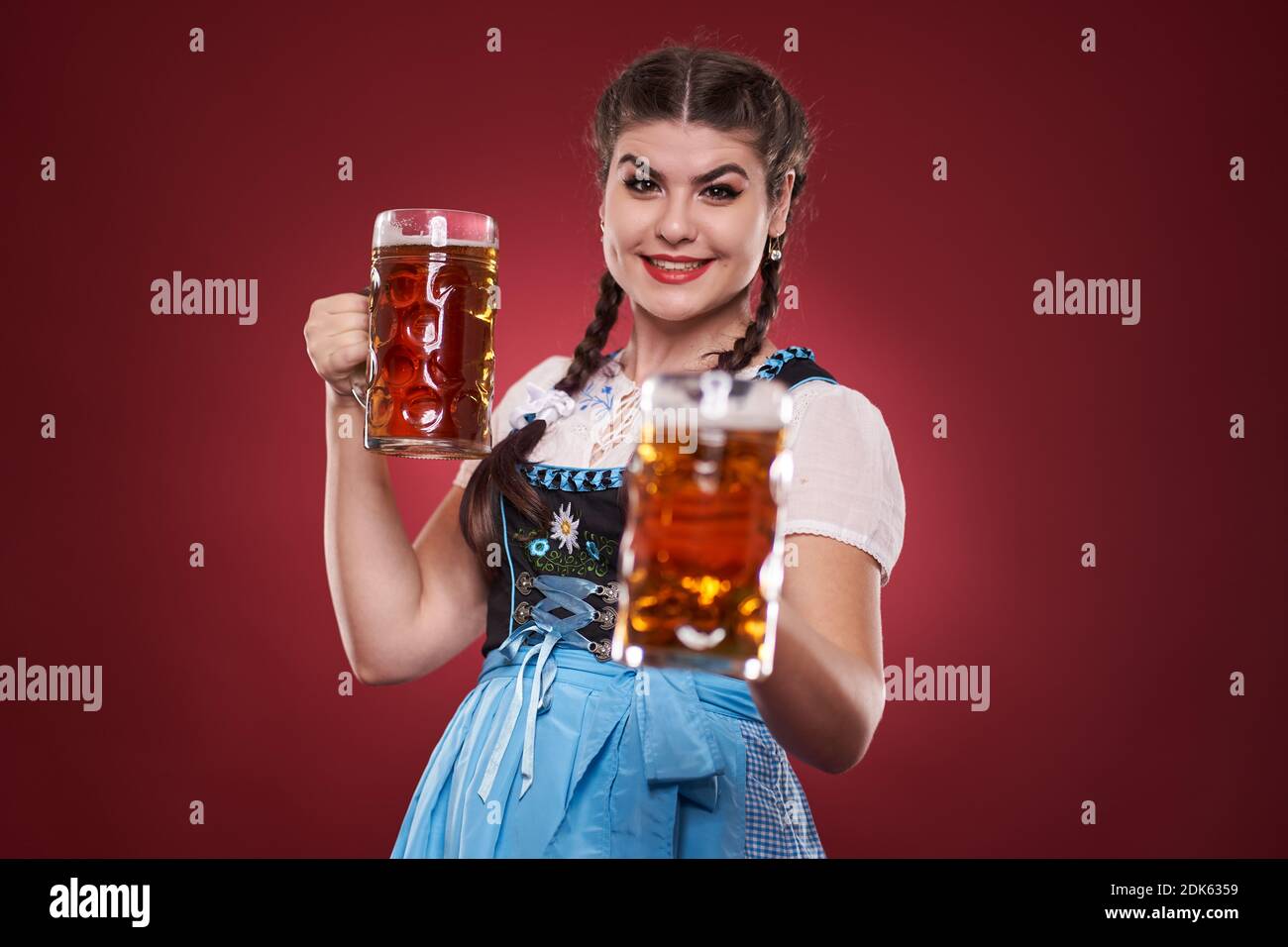 German girl in traditional costume with two large pints of pale ale ...