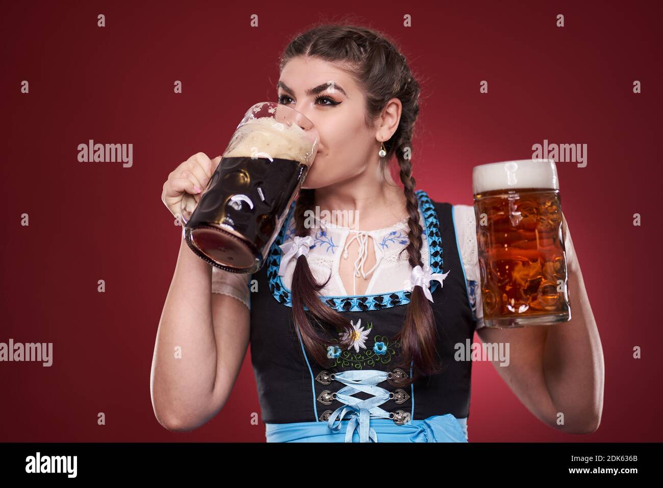 Young German girl in traditional costume with two pints of beer, brown ...