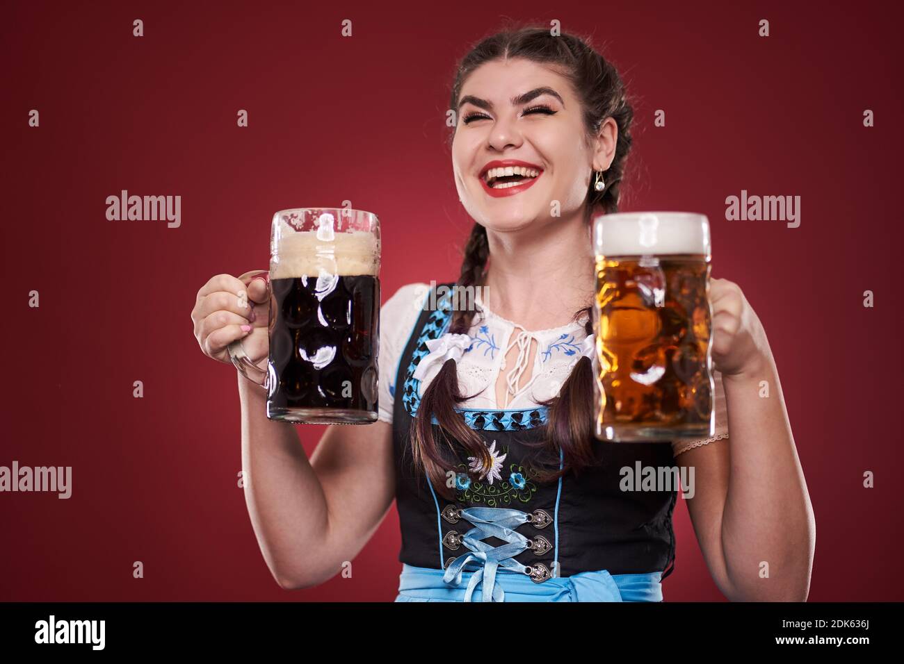 Young German girl in traditional costume with two pints of beer, brown ...
