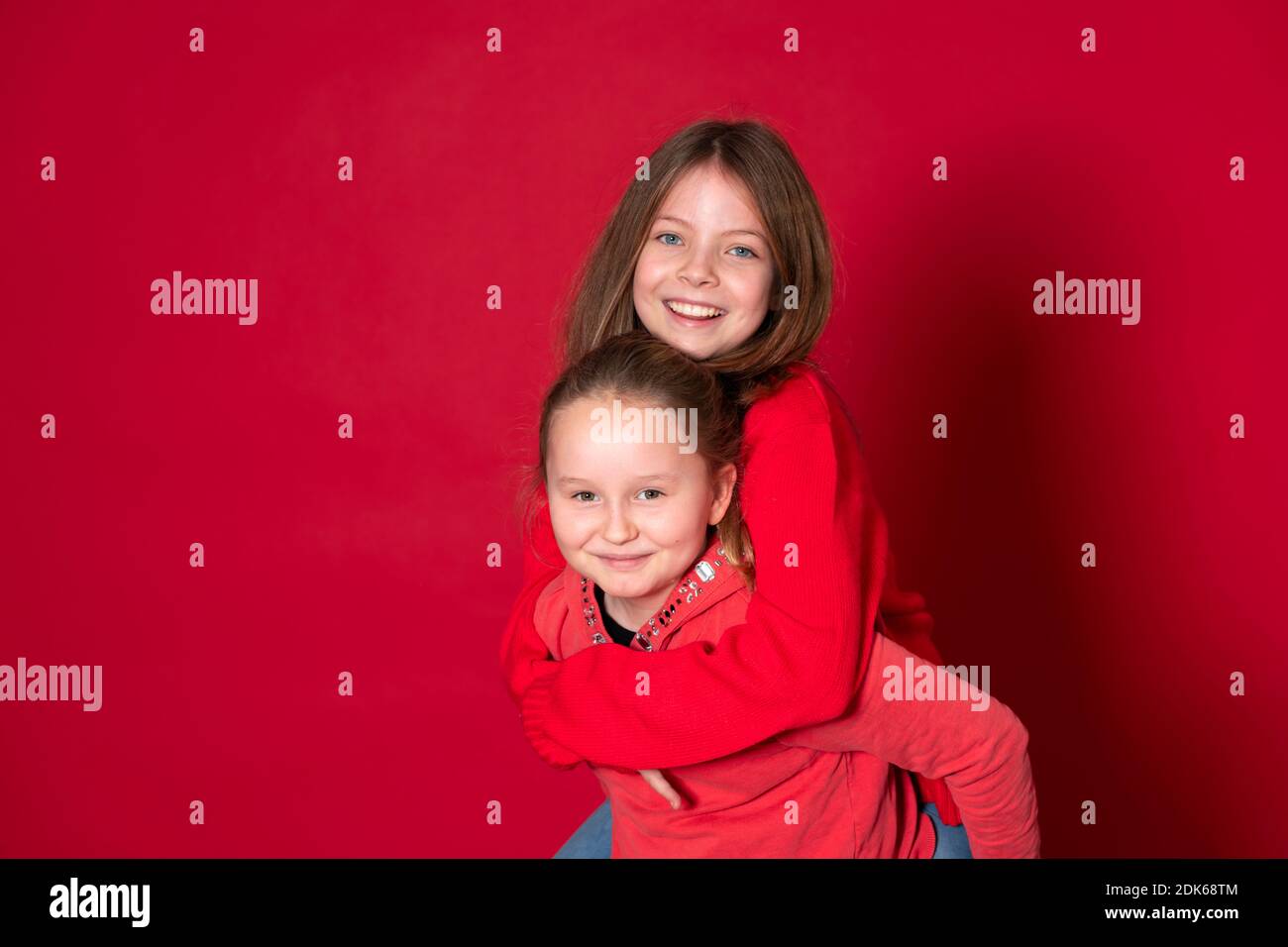 best girlfriends wearing red clothes in front of red background Stock ...