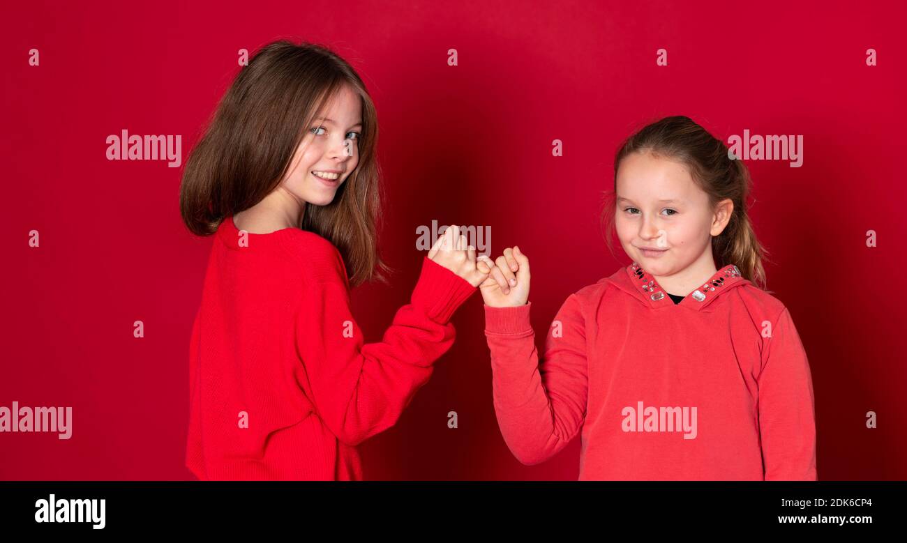 best girlfriends wearing red clothes in front of red background Stock ...