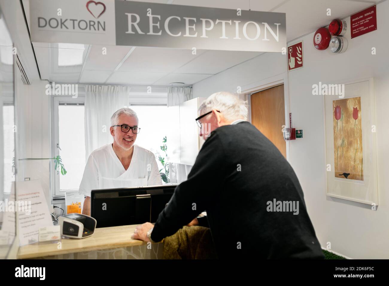 Senior man at reception in doctor's surgery Stock Photo - Alamy