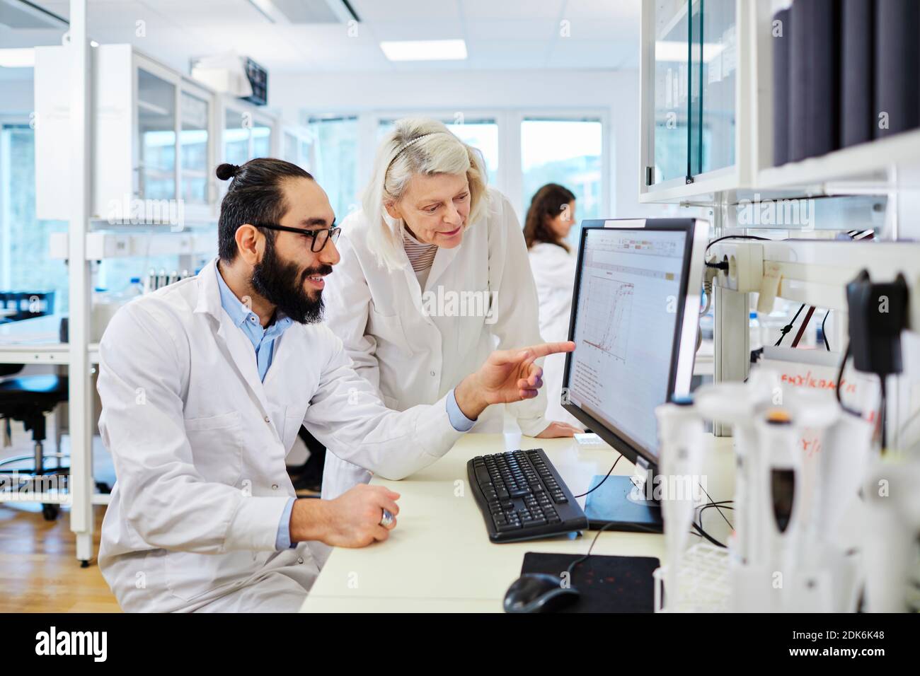 Scientists analyzing chart on computer screen Stock Photo - Alamy