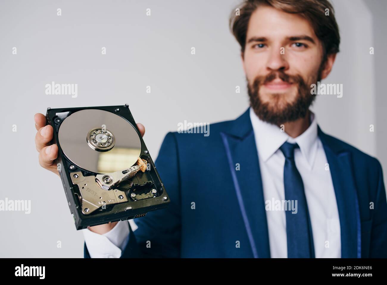 a man in a suit holds an unassembled hard drive in his hand and a gray ...