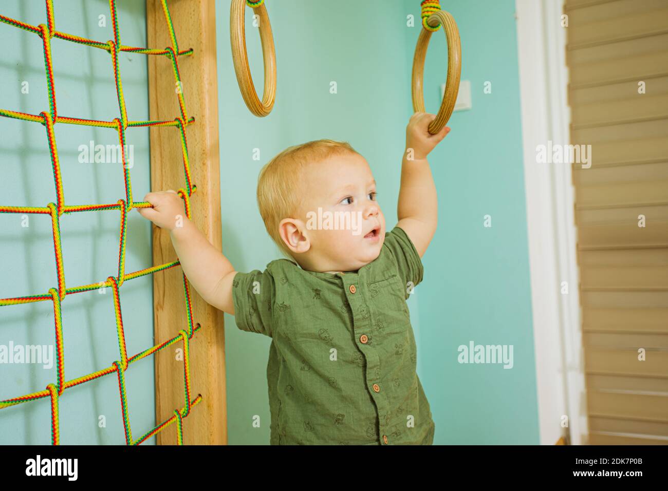 Small kid trying to reach wooden gymnastic rings Stock Photo - Alamy