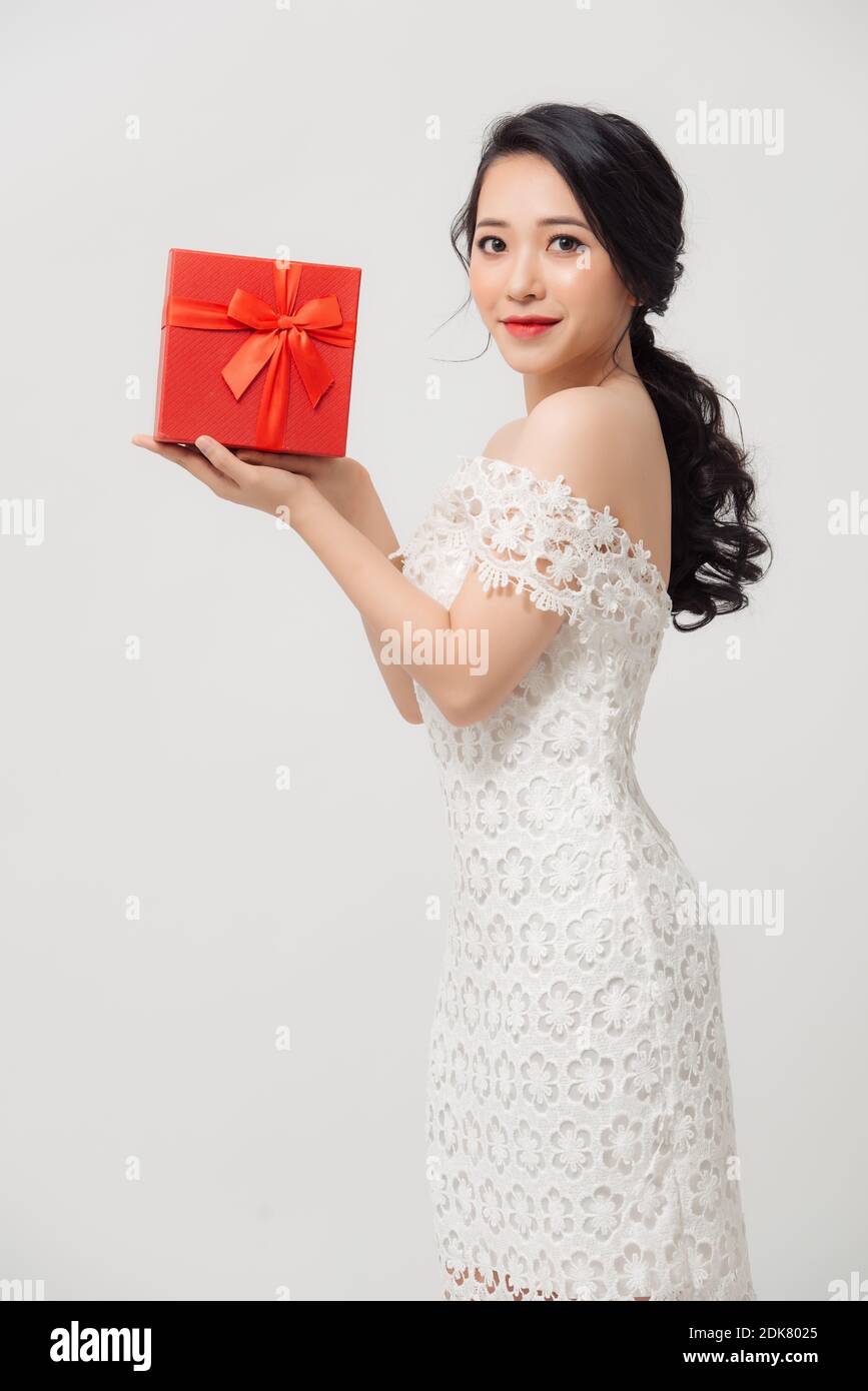 Happy beautiful young Asian woman holding gift box isolated over white ...