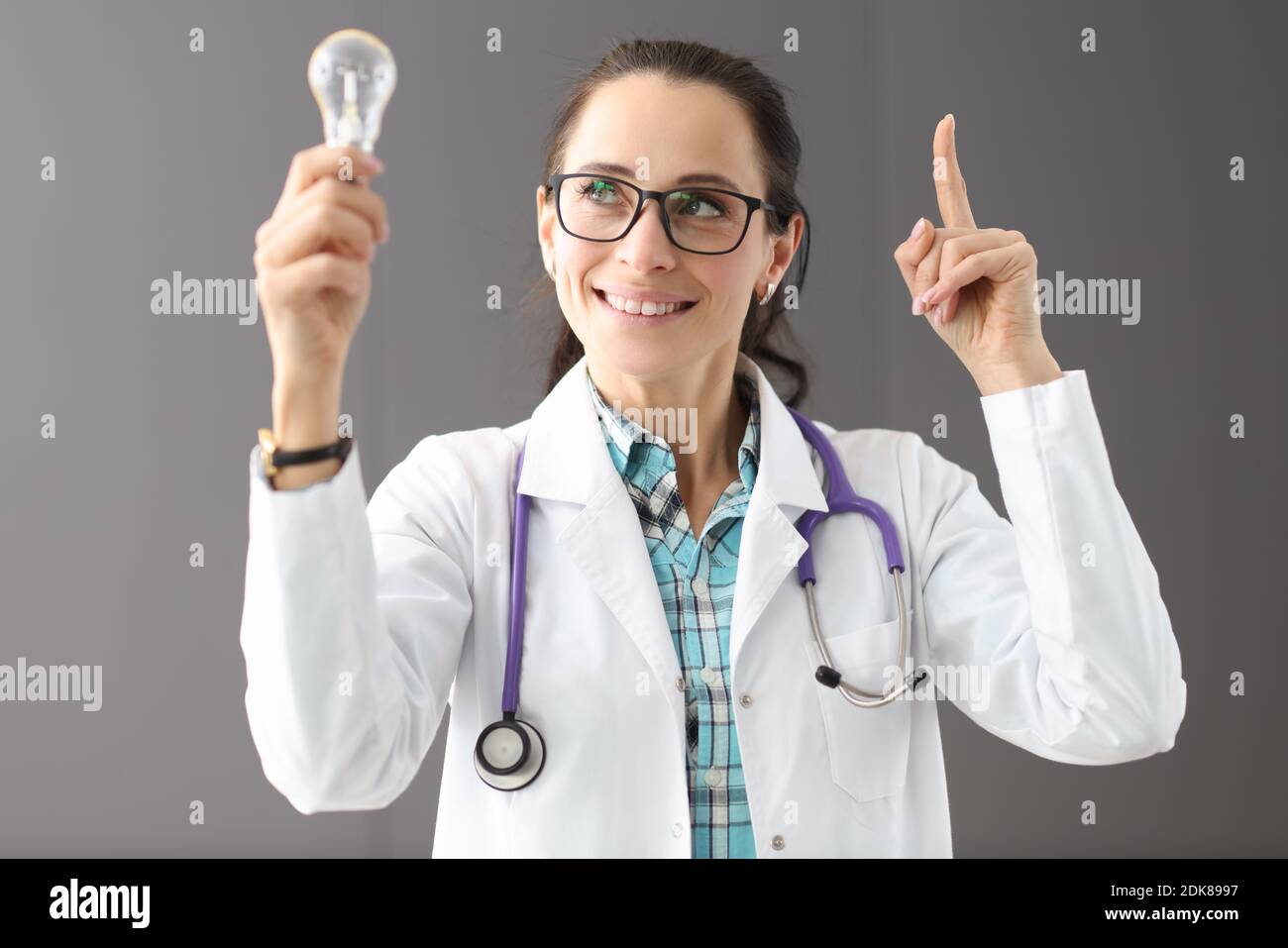 Smiling female doctor holding light bulb and thumb up Stock Photo - Alamy