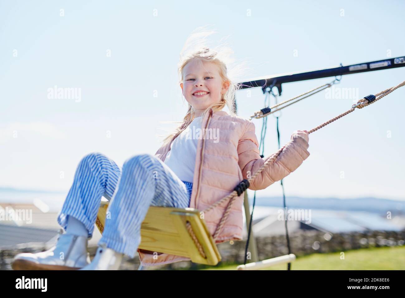 Girl swinging on playground Stock Photo - Alamy
