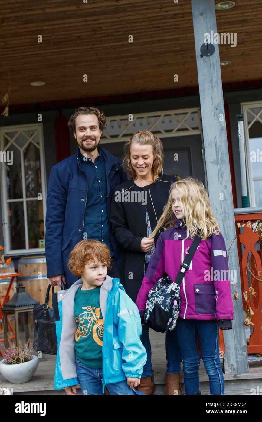 Parents with two children standing in front of house Stock Photo - Alamy