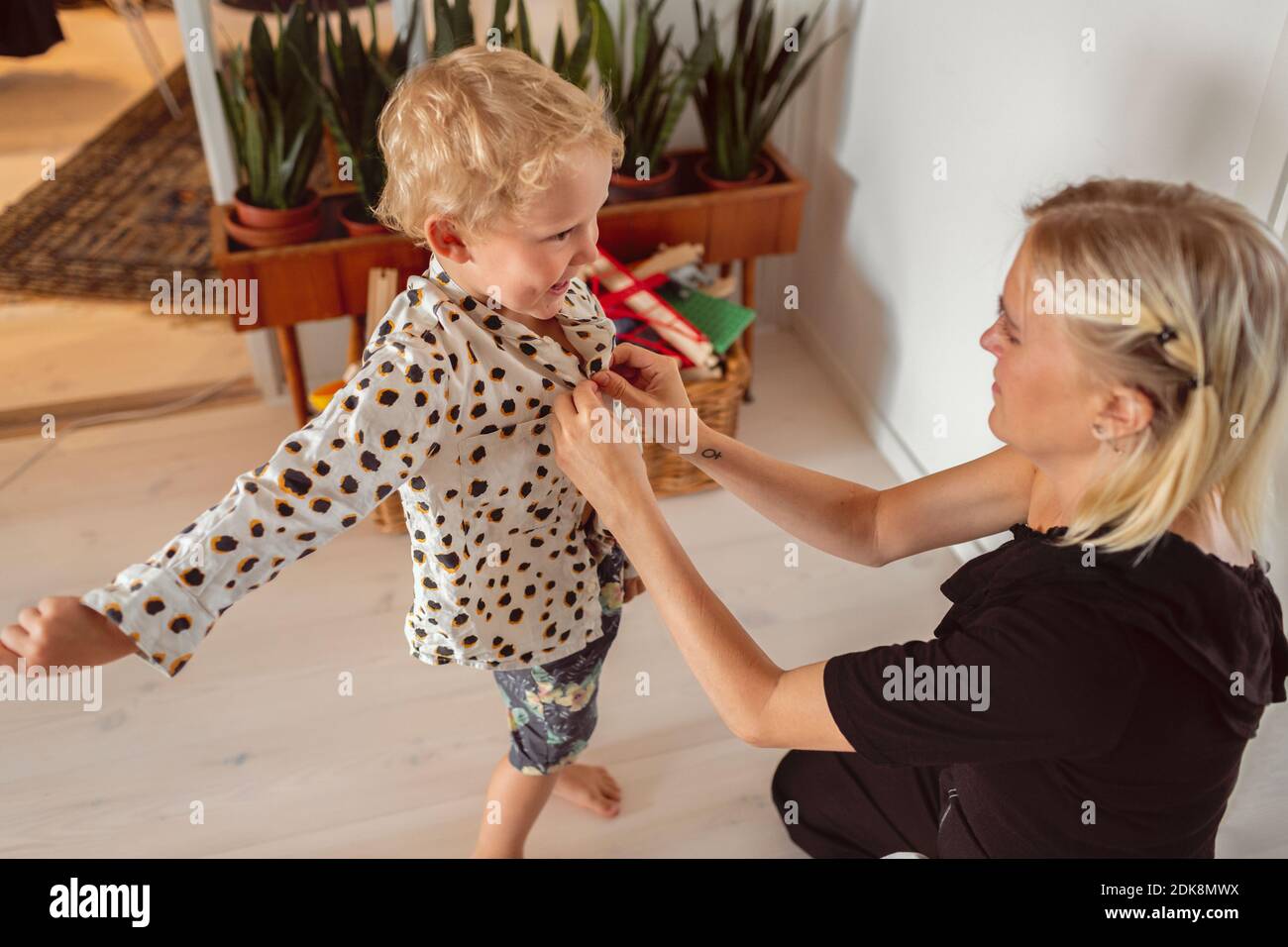 Mother helping son to get dressed Stock Photo - Alamy