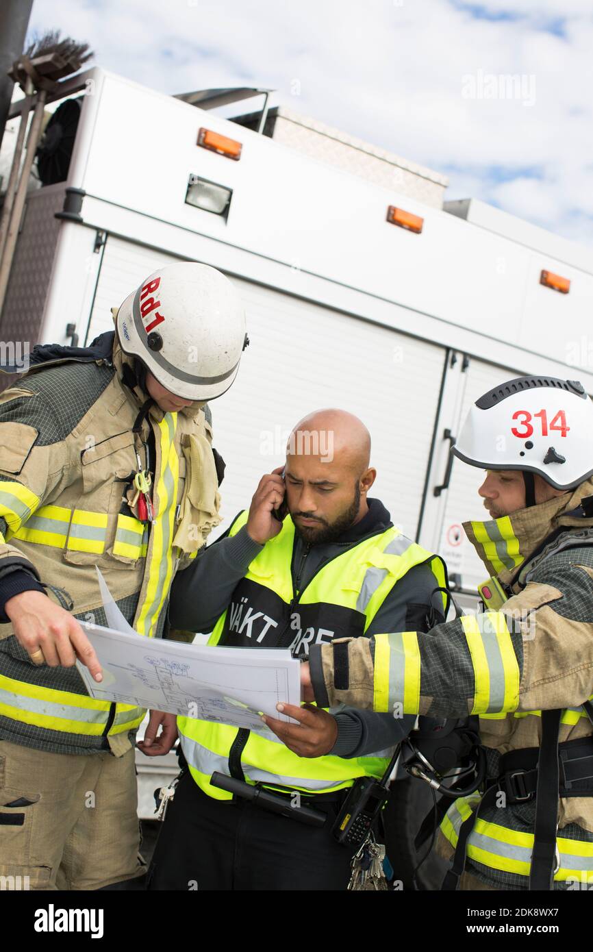 Security guard and firefighters discussing plan Stock Photo - Alamy