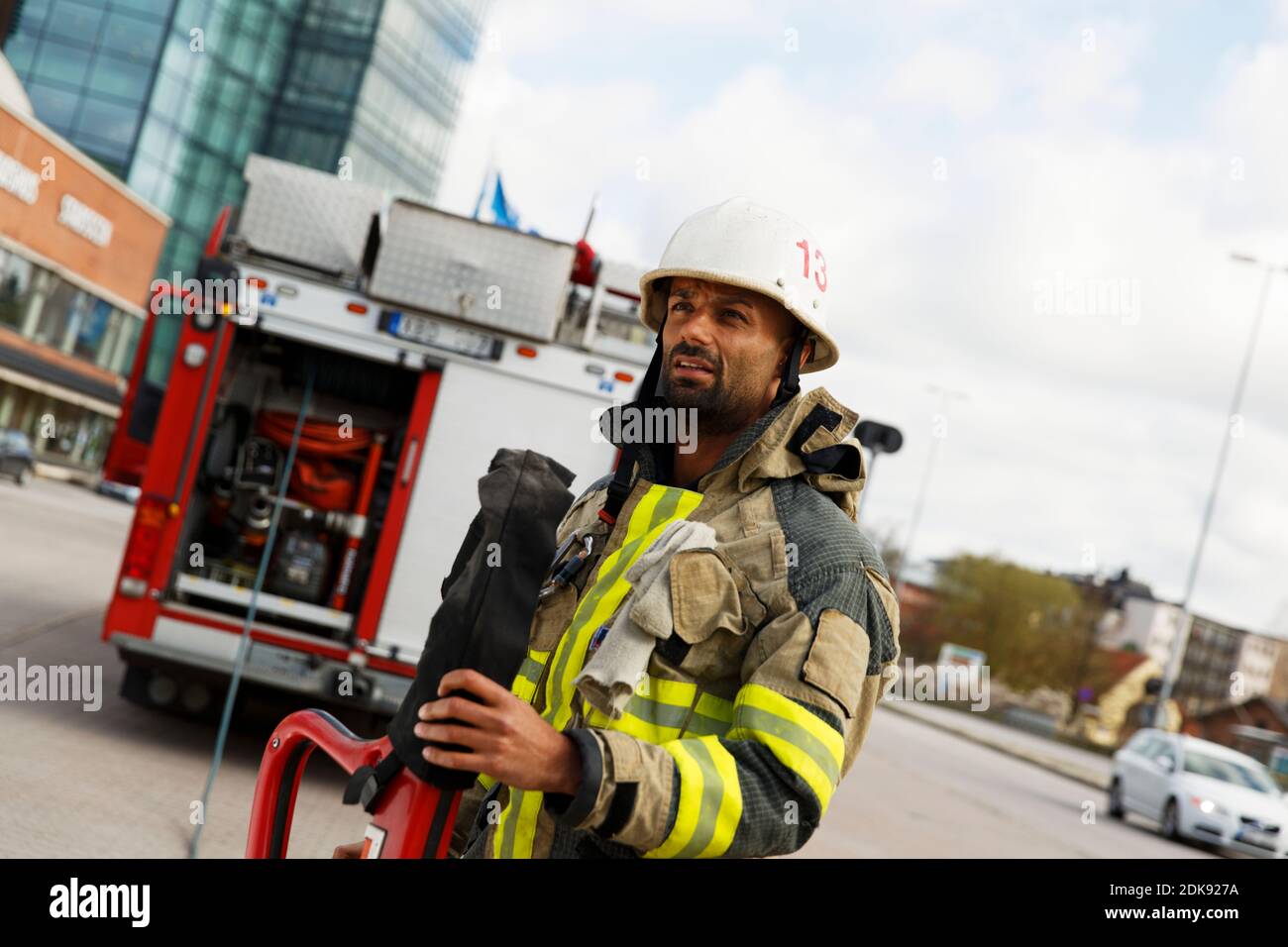 Firefighter standing by fire engine Stock Photo - Alamy