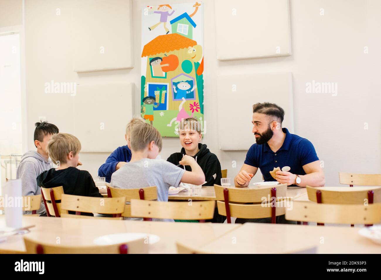 Teacher with children in classroom having lunch Stock Photo - Alamy