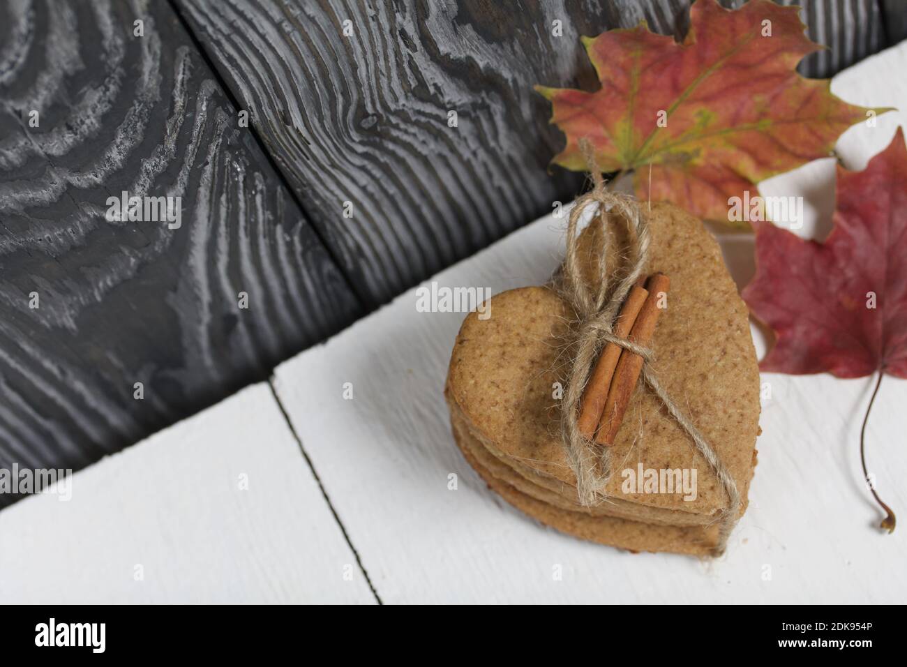 Gingerbread cookies tied with twine and autumn maple leaves. On boards ...