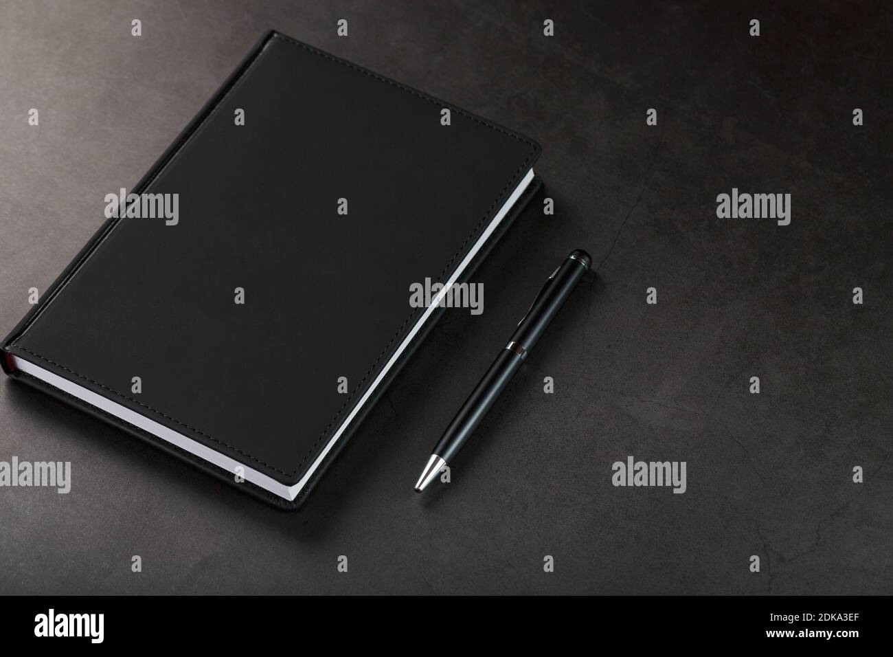 Black Notepad with a black pen on a black background. Top view ...