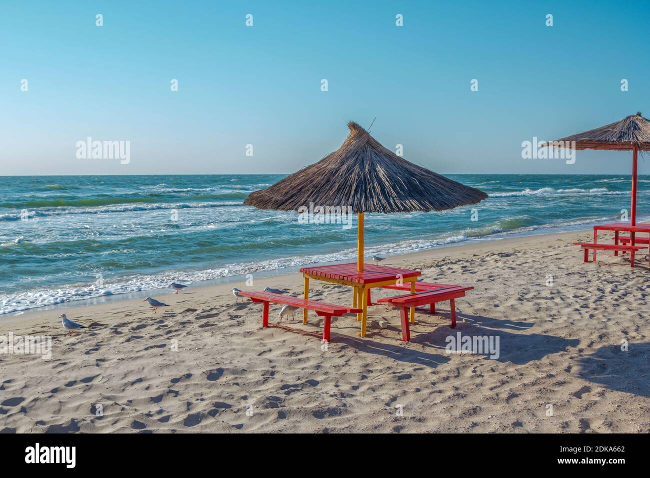 Summer landscape: table, benches and shade umbrella on the beach ...