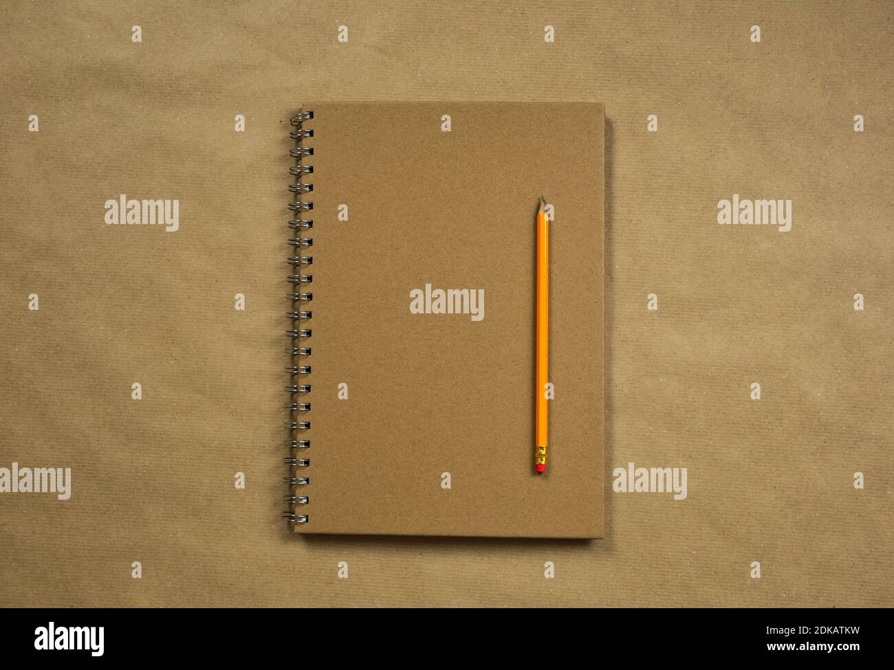 Brown notebook and classic pencil on brown plain paper background ...