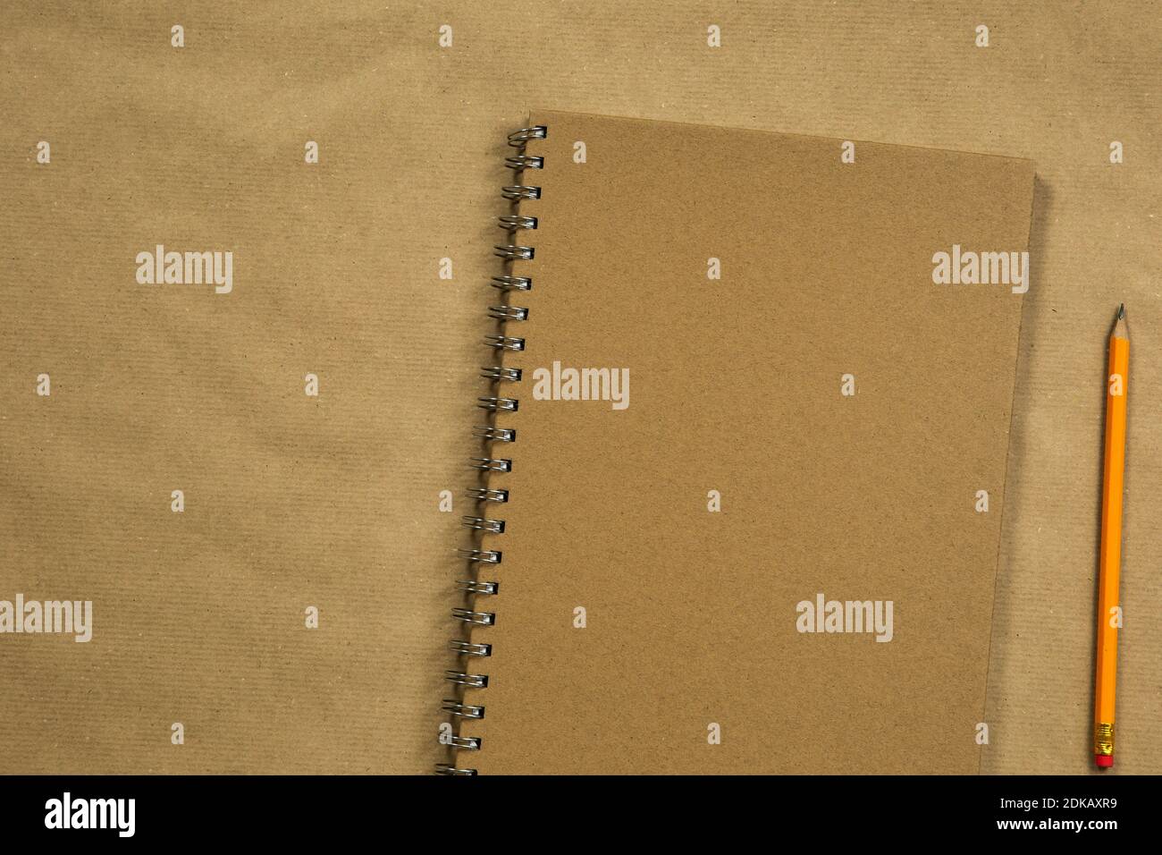 Brown notebook and classic pencil on brown plain paper background ...